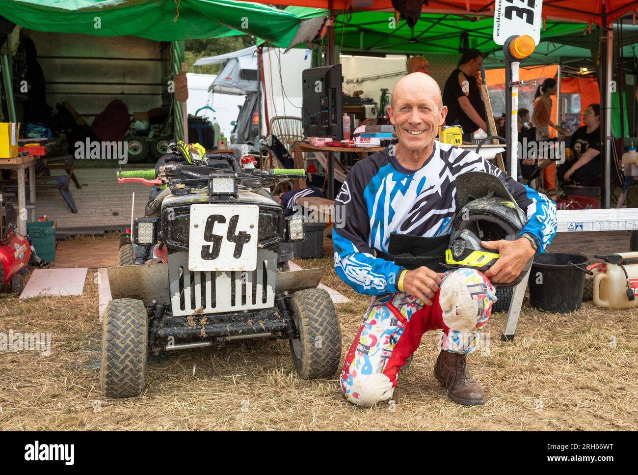 Leon Clark, a racing lawn mower driver kneels next to his racing mower ...