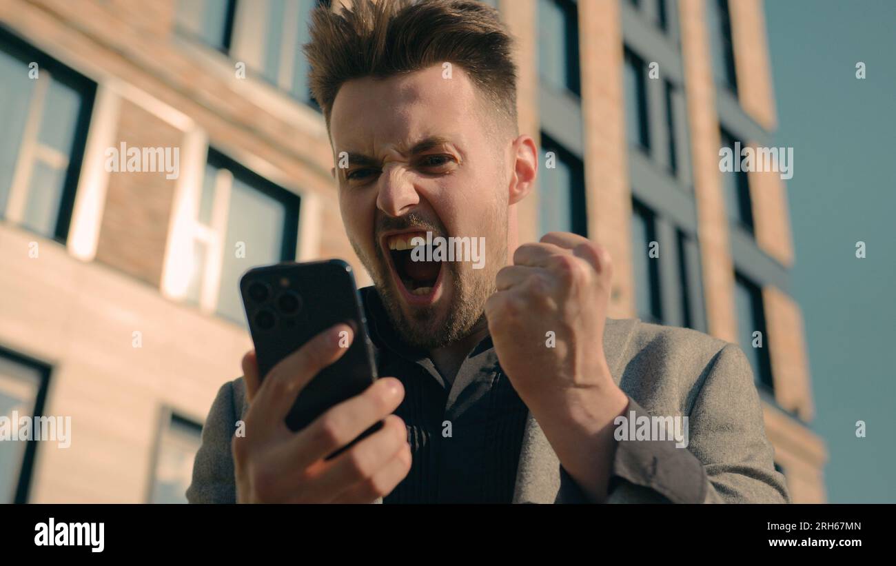 Angry mad caucasian businessman business man using phone reading bad ...