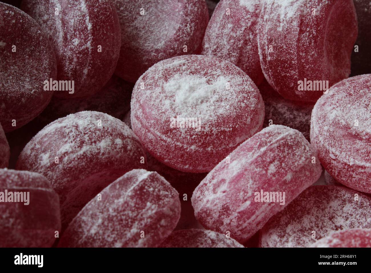 Close up macro of hard red candies covered in fine white sugar. Sweets ...