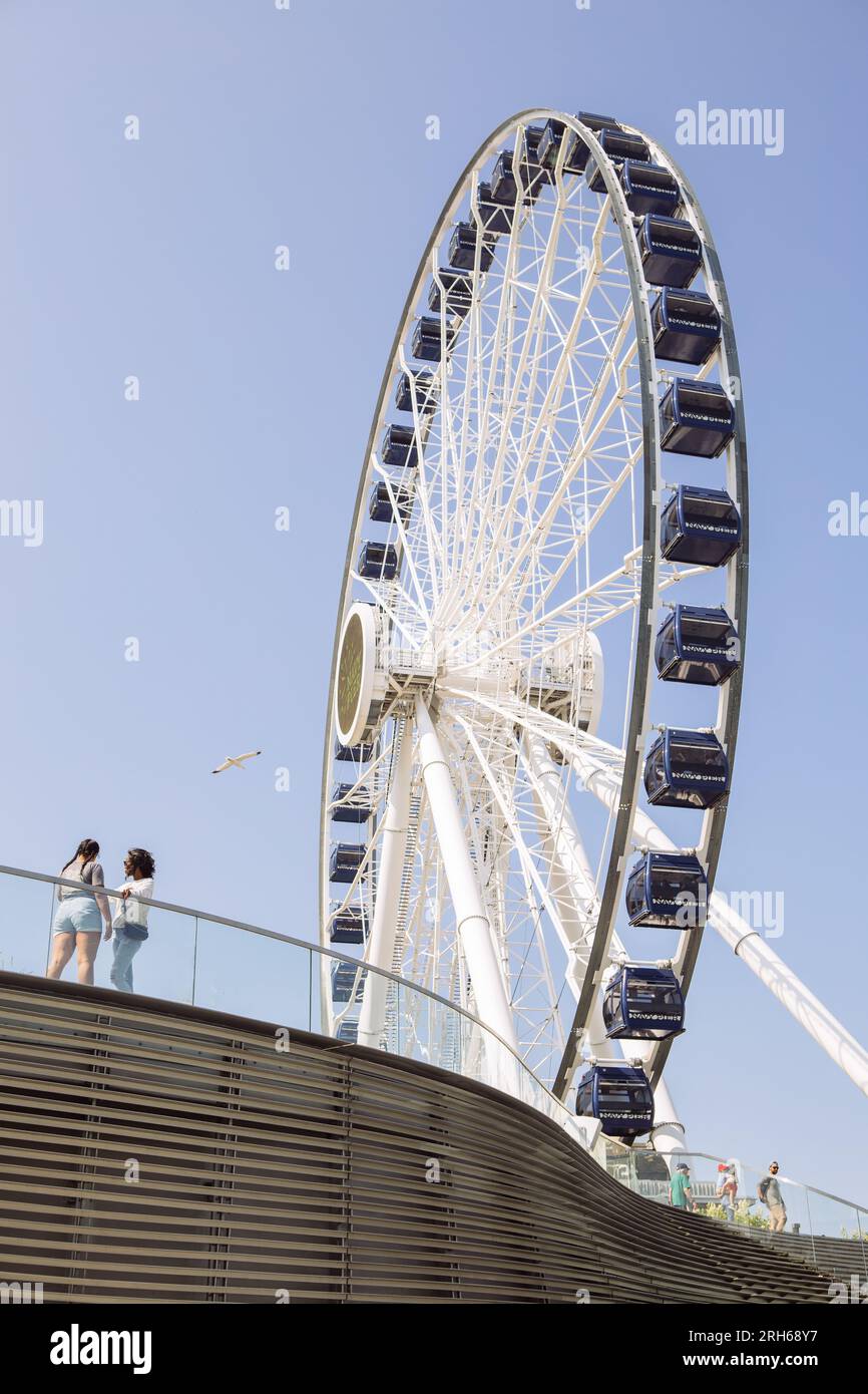 Navy Pier Centennial wheel from down with two tourists waiting in a ...