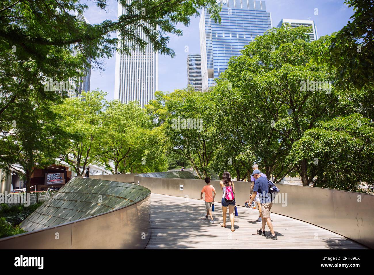 Family walking through the BP Pedestrian Bridge clad in brushed ...