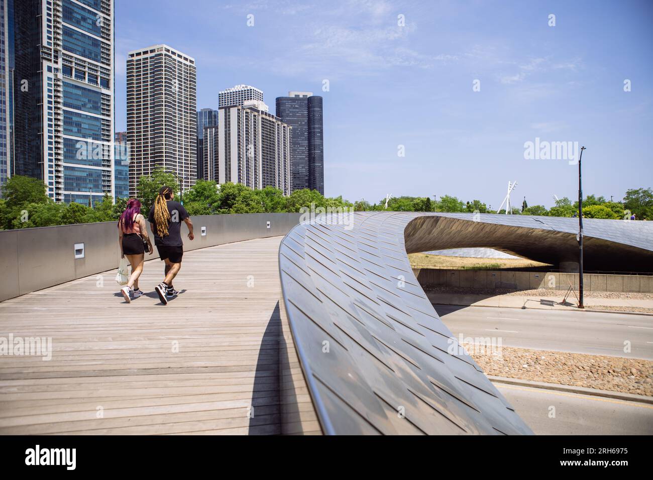Couple crossing the BP Pedestrian Bridge clad in brushed stainless ...