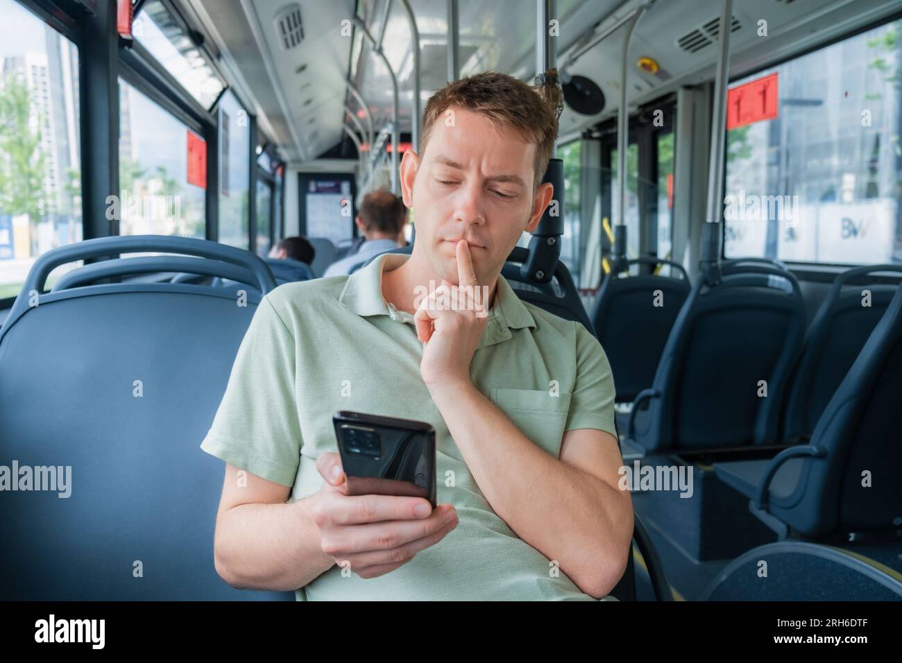 Thoughtful man is reading emails on his smartphone connected to public ...