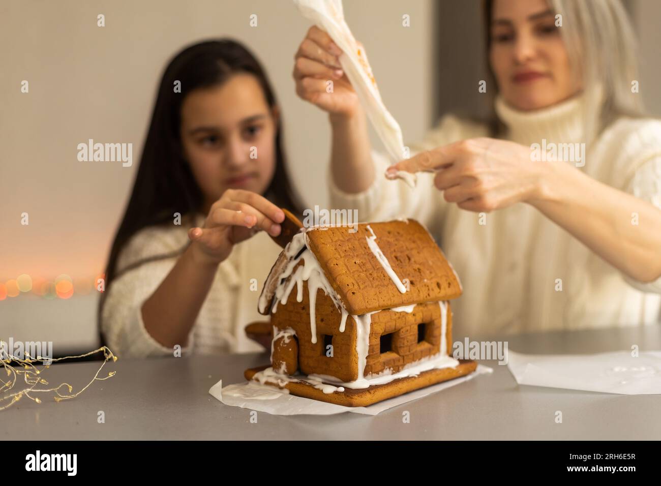 mother and daughter decorating gingerbread house. Beautiful living room ...
