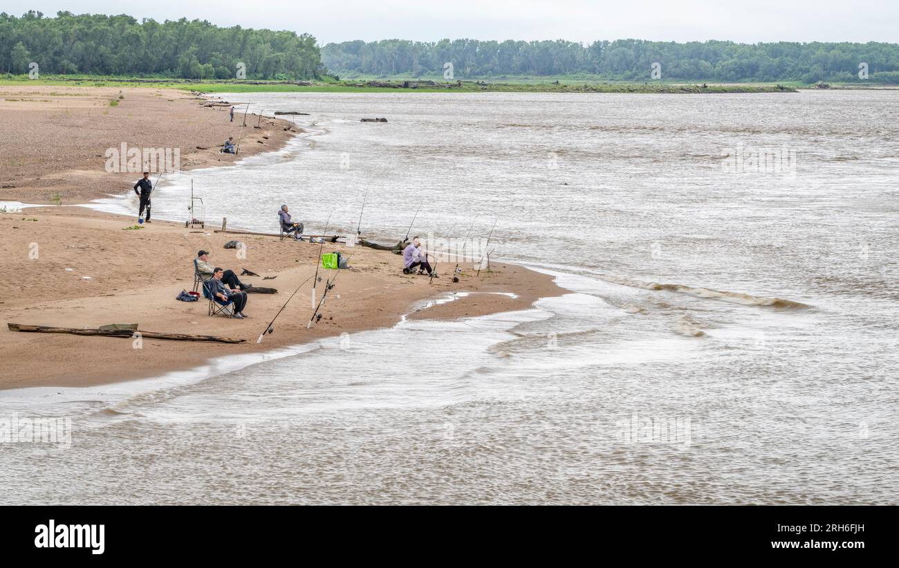 group of men is fishing from a sandbar on the Mississippi River at ...