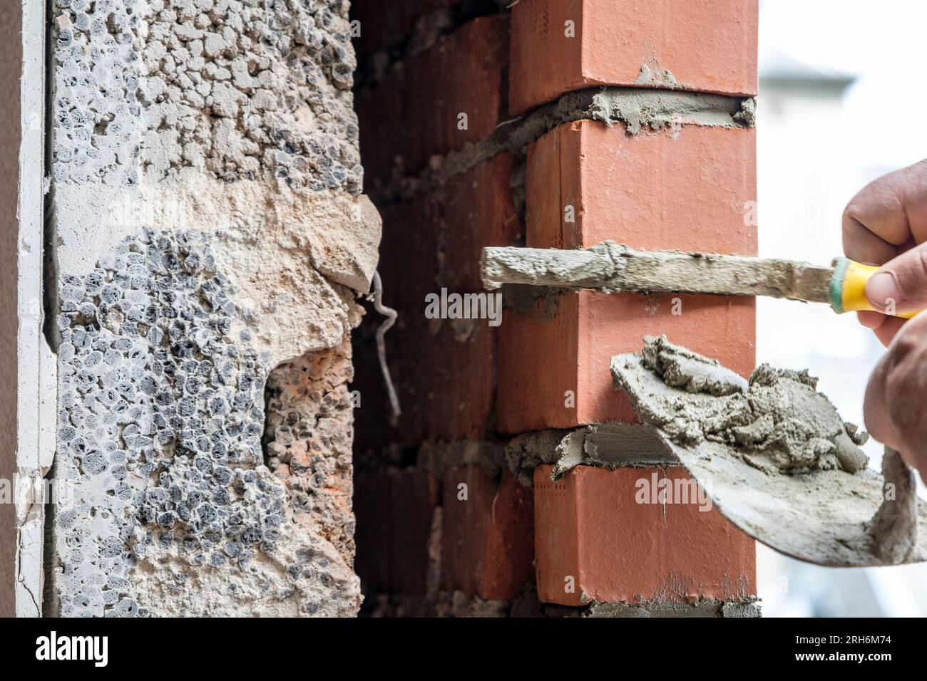 Mason at work to replace a window - Filling the joints with a sand and ...