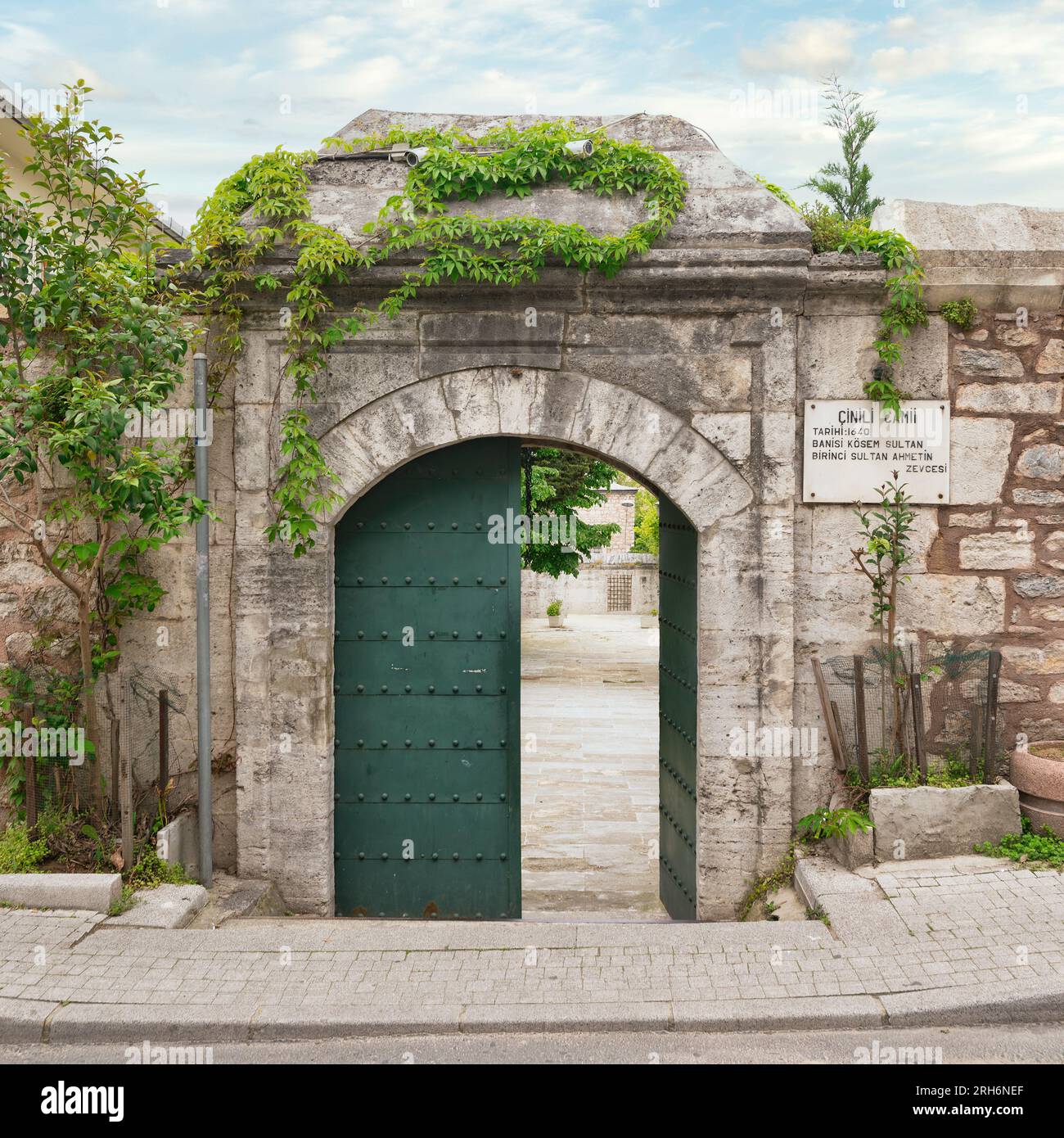 Arched entrance with green metal door in brick stone wall leading to ...
