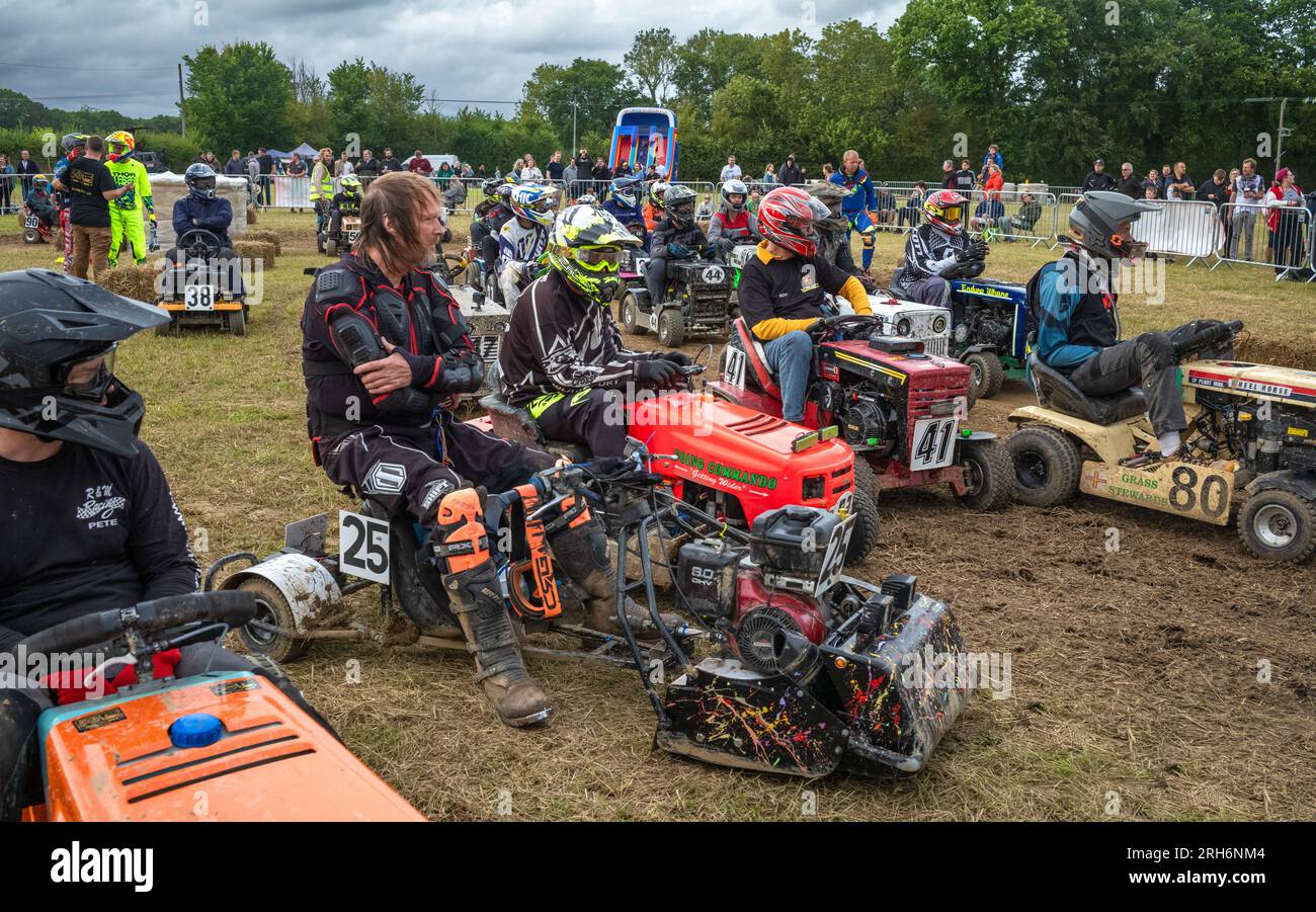 Drivers sit on their racing lawn mowers while they wait to be assigned ...