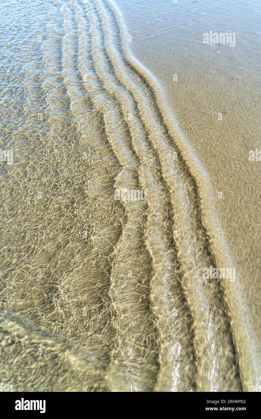 Ocean water forms patterns over sand as it reaches shore in Moclips ...
