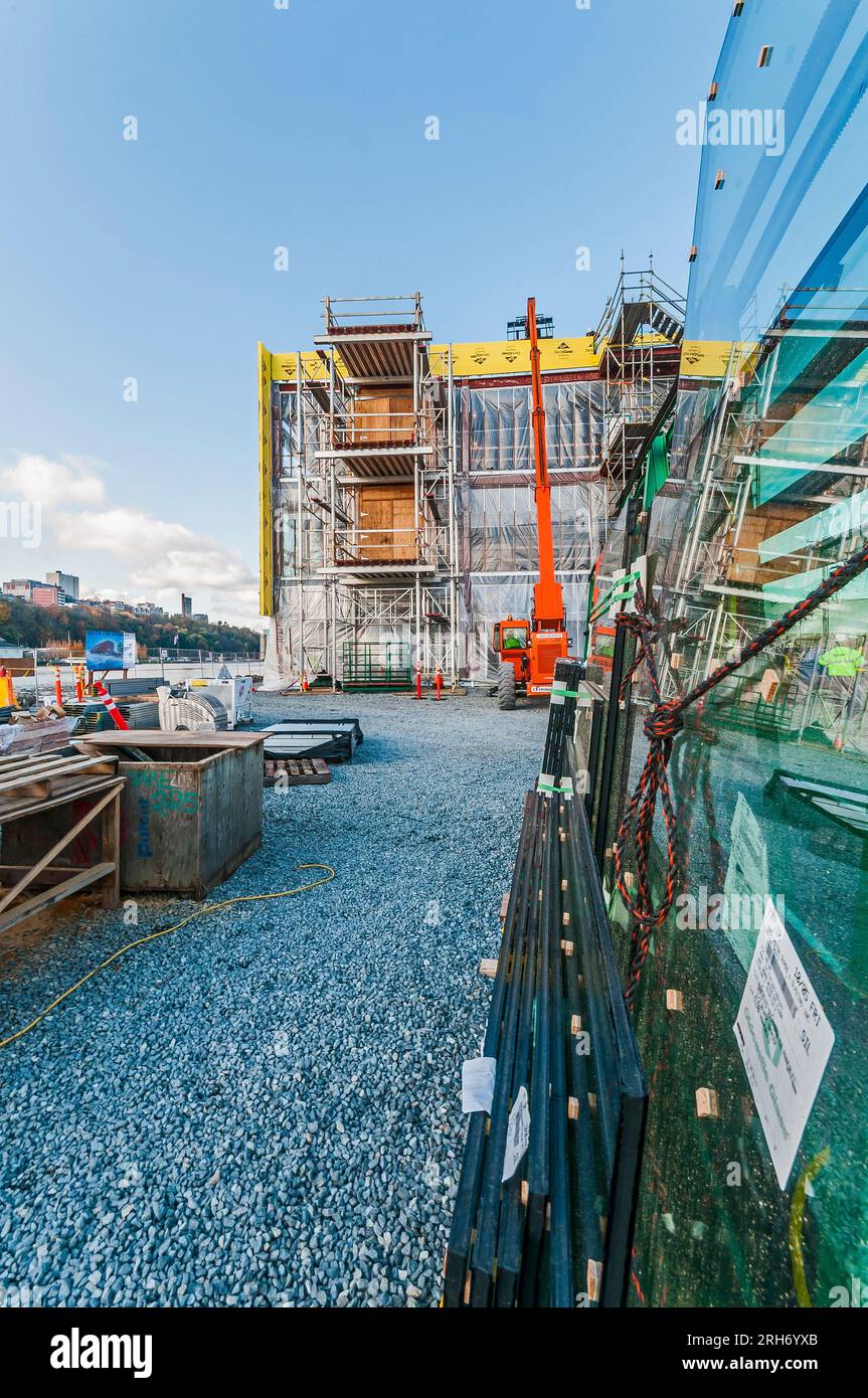 An orange rental high-lift with its arm extended to roof of building at ...