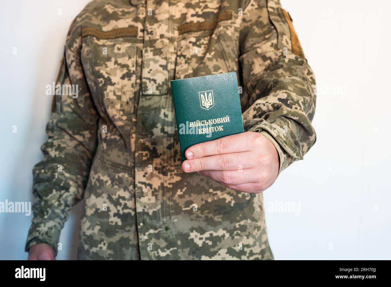 Soldier in camouflage holds military identity card in left hand ...