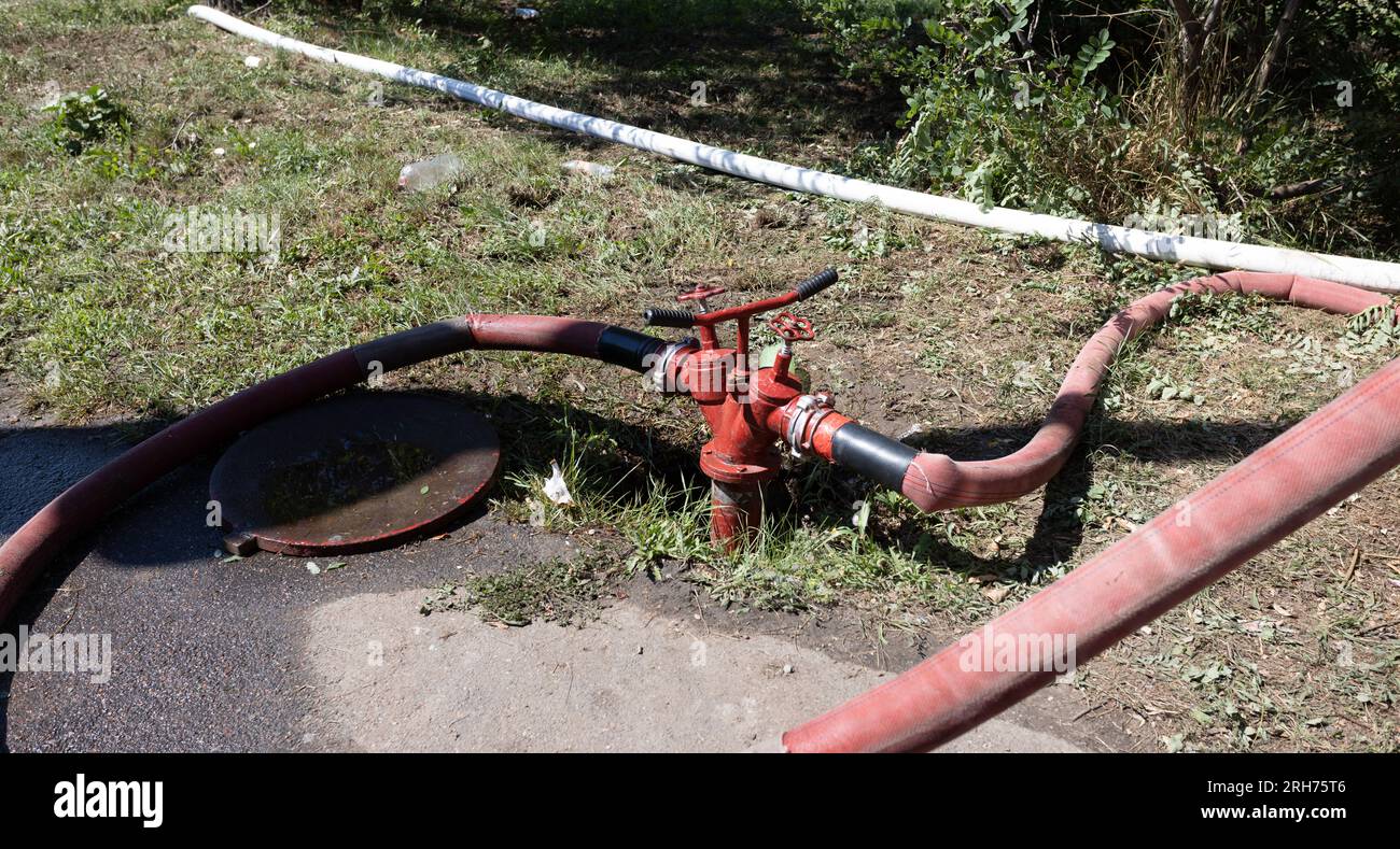 Old leaky hoses of a fire engine pump water from a fire hydrant while ...