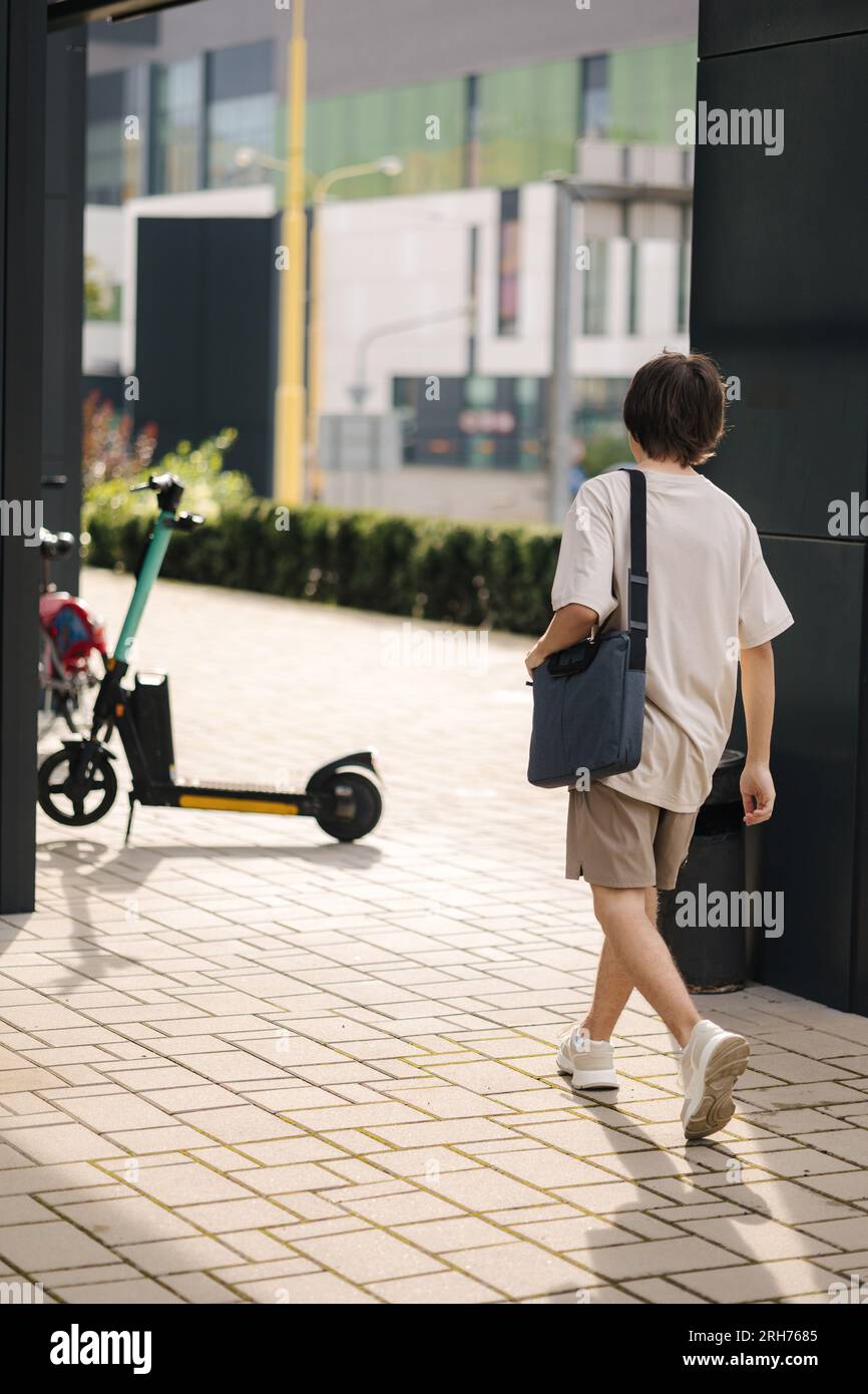 Back view of delivery boy go to his electric scooter Stock Photo - Alamy