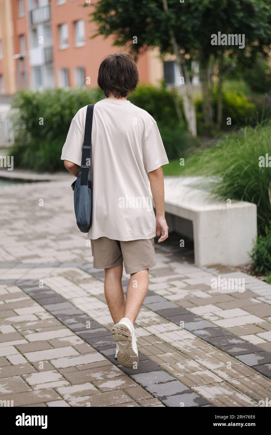 Back view of teenage boy student with laptop bag go home after college ...