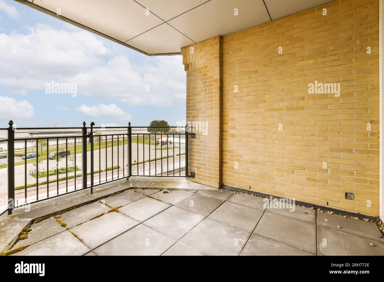 a balcony with yellow brick walls and black metal railings on the right ...