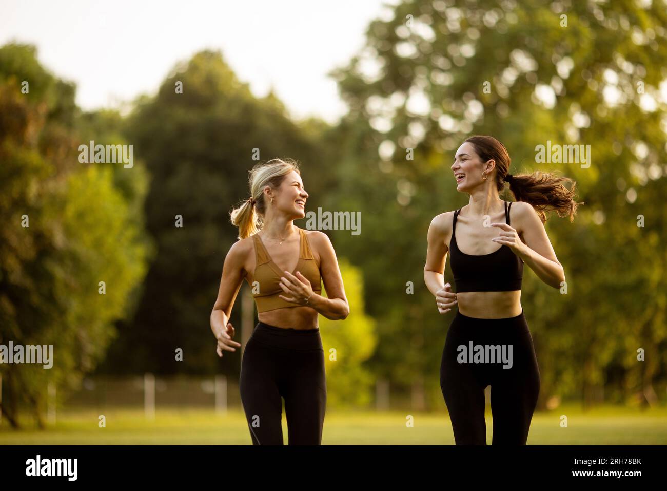 Two pretty young women running in the park Stock Photo - Alamy