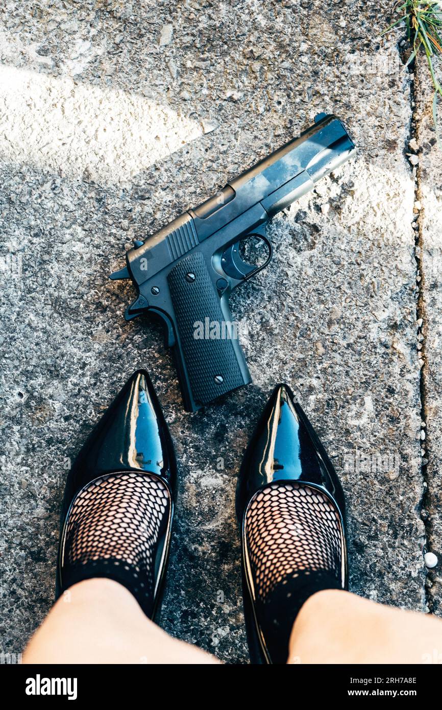 Top View. Woman standing next to a gun and wearing black heels and ...
