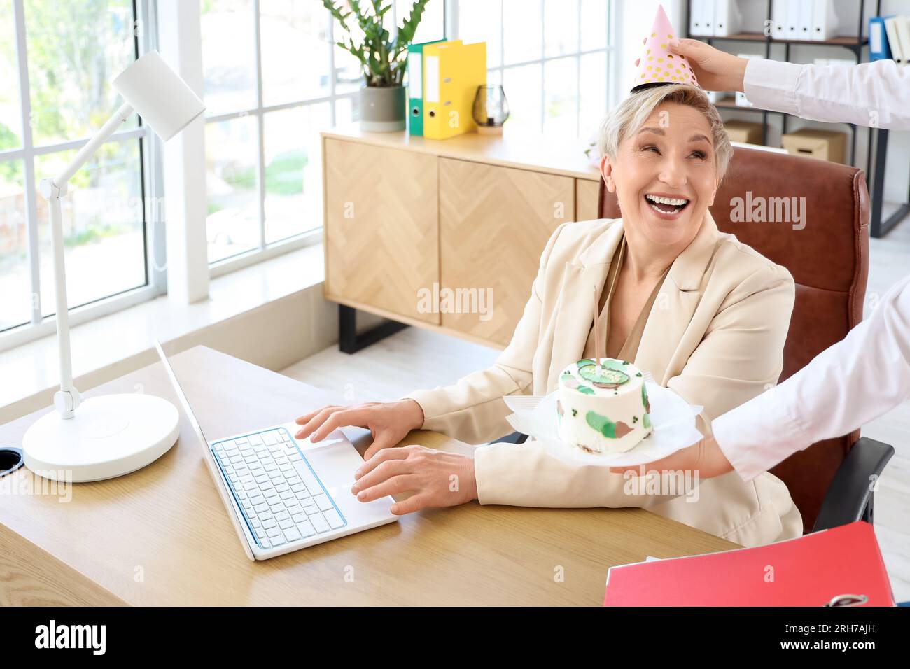 Mature woman receiving birthday cake from colleague in office Stock ...