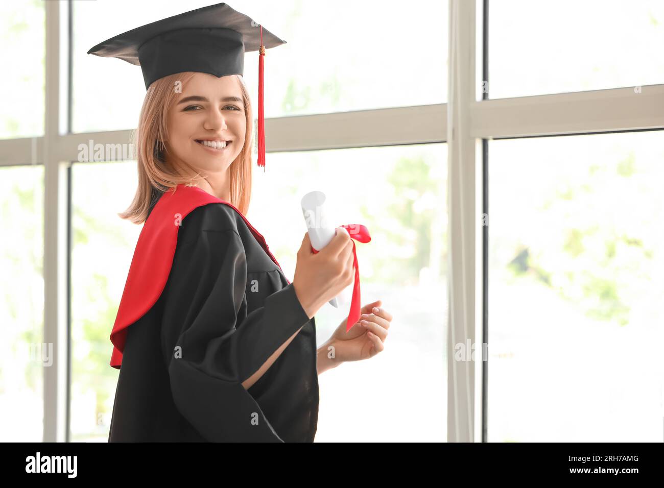 Female graduate student with diploma near window in room Stock Photo ...