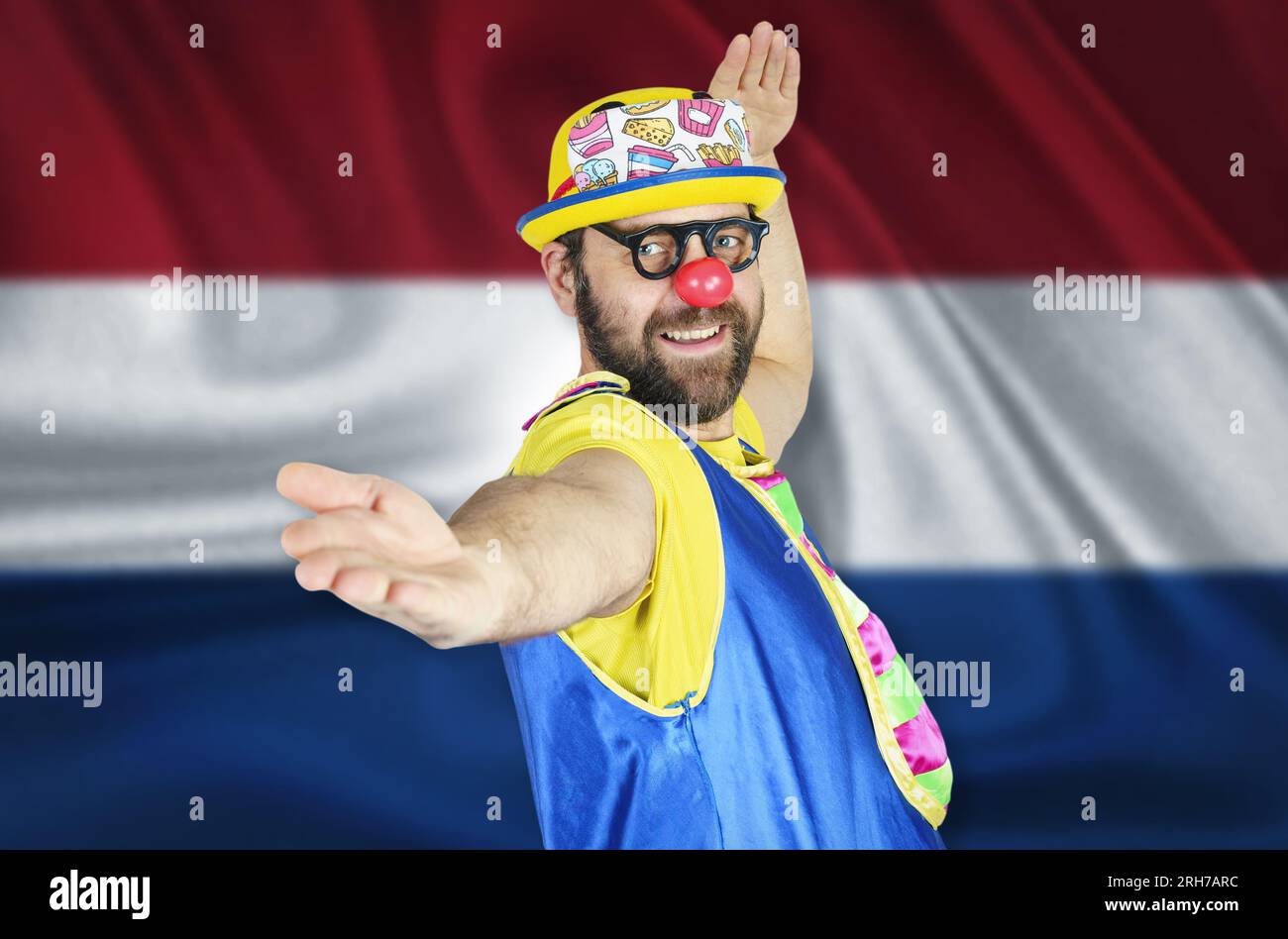 A cheerful clown stands in a welcoming pose against the background of ...