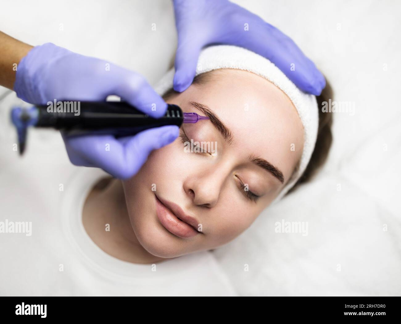 Beautician hand doing eyebrow permanent makeup on young attractive ...