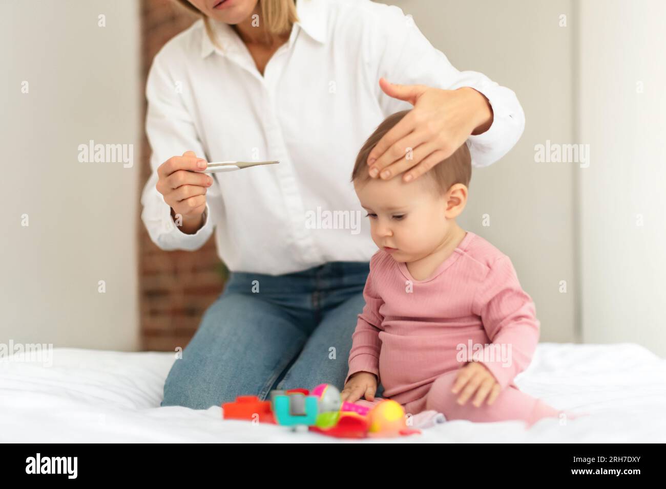 Infant health problems. Mother checking temperature to her sick child ...