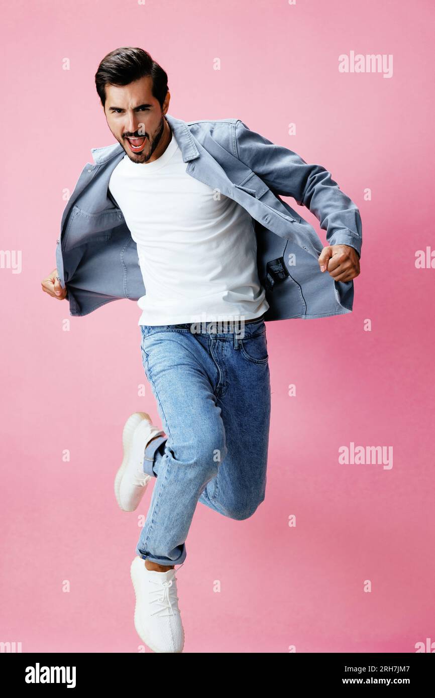 Man with beard jumping on pink background in white T-shirt and jeans ...