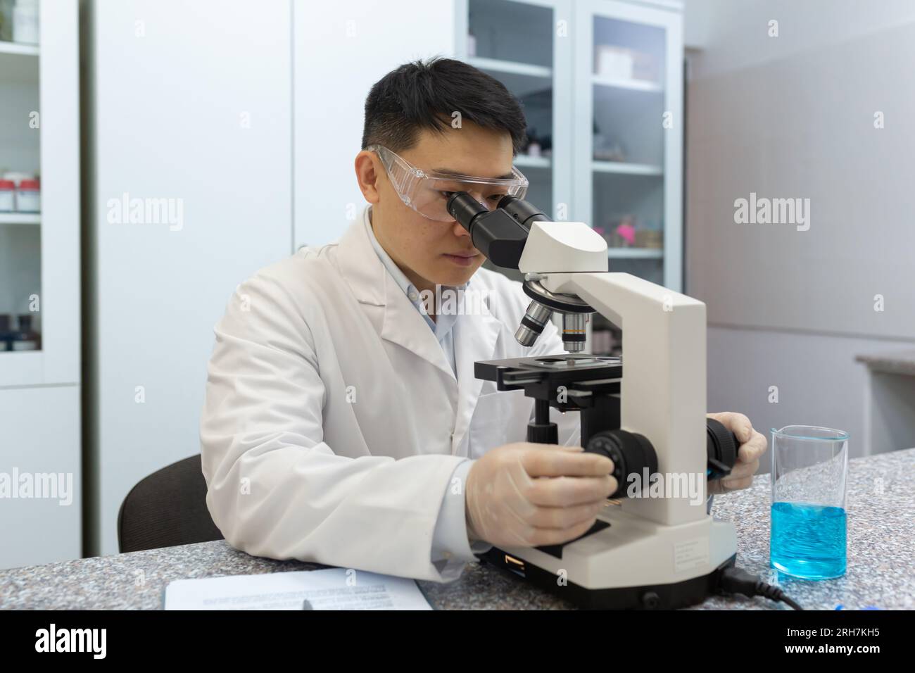 Young Asian male scientist, doctor working in laboratory under ...