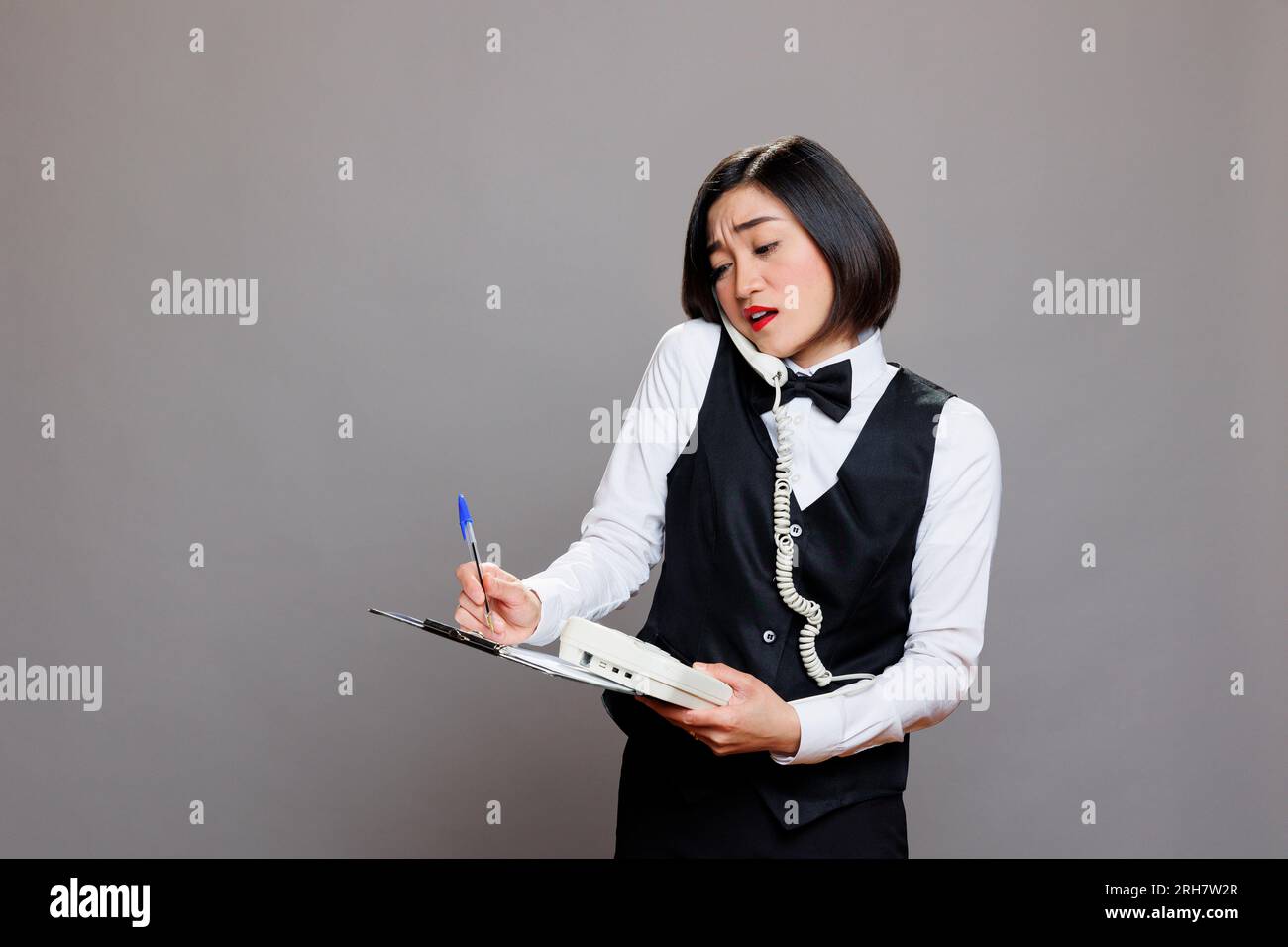 Asian woman receptionist checking information on clipboard while ...