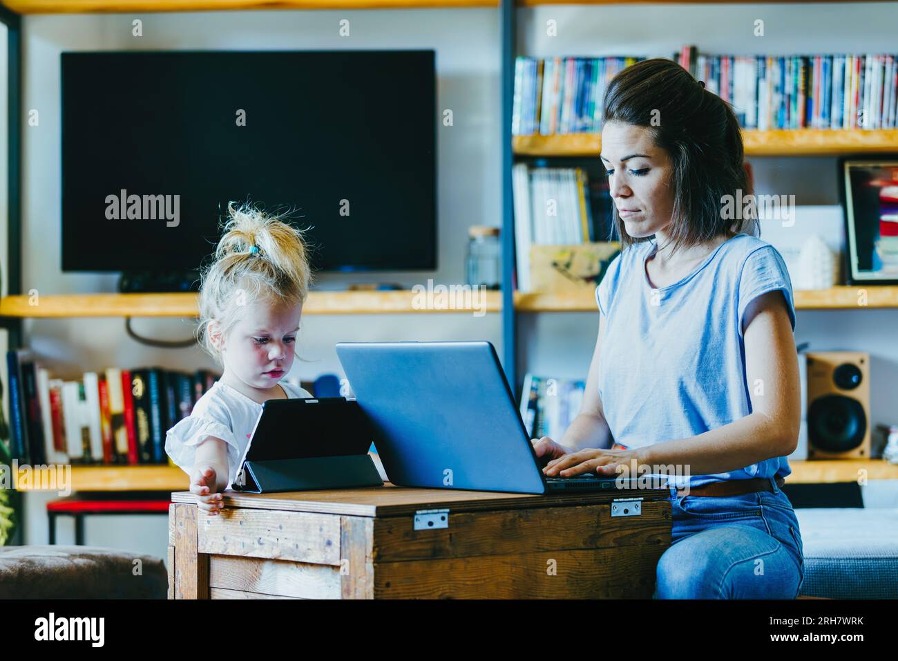 Mom and daughter in the living room, each using their own mobile device ...