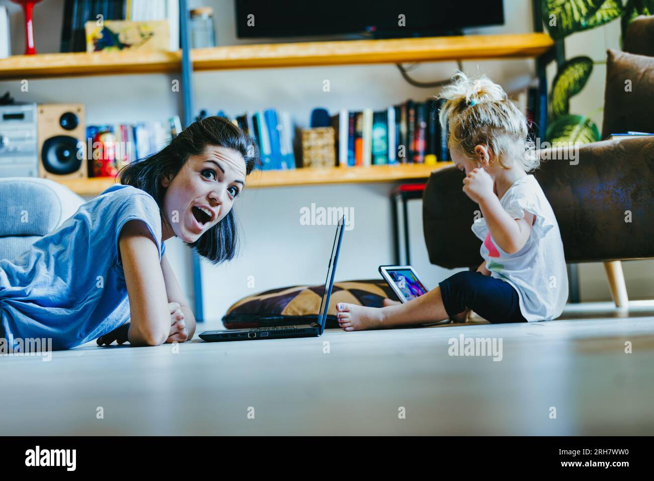 Mom and daughter each with a device, girl playing games, mom working ...