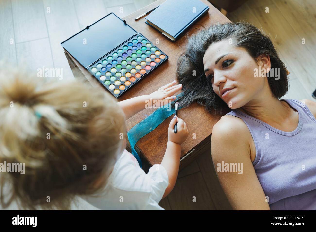 Playing in the living room, mom and daughter enjoy makeup, become ...