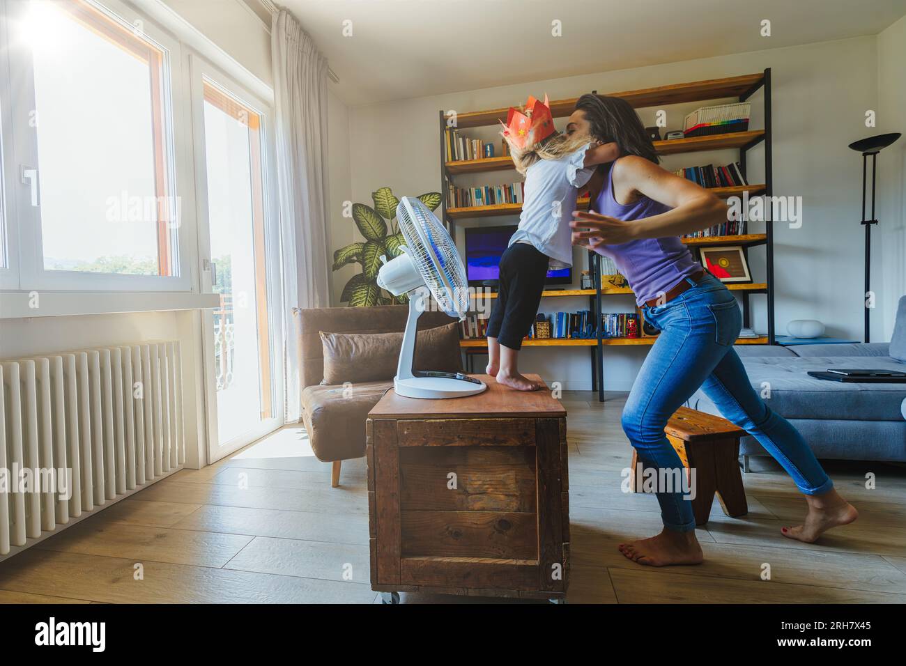 Dancing, flying with a fan, mother and daughter find joyful refreshment ...