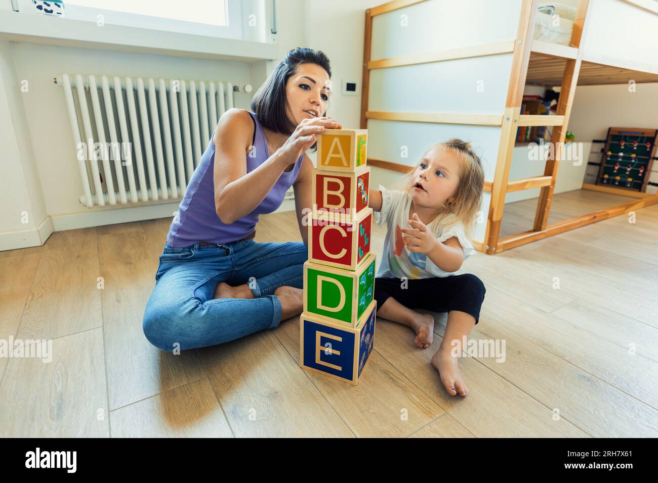 In a room filled with wooden toys, a young woman and her blonde ...