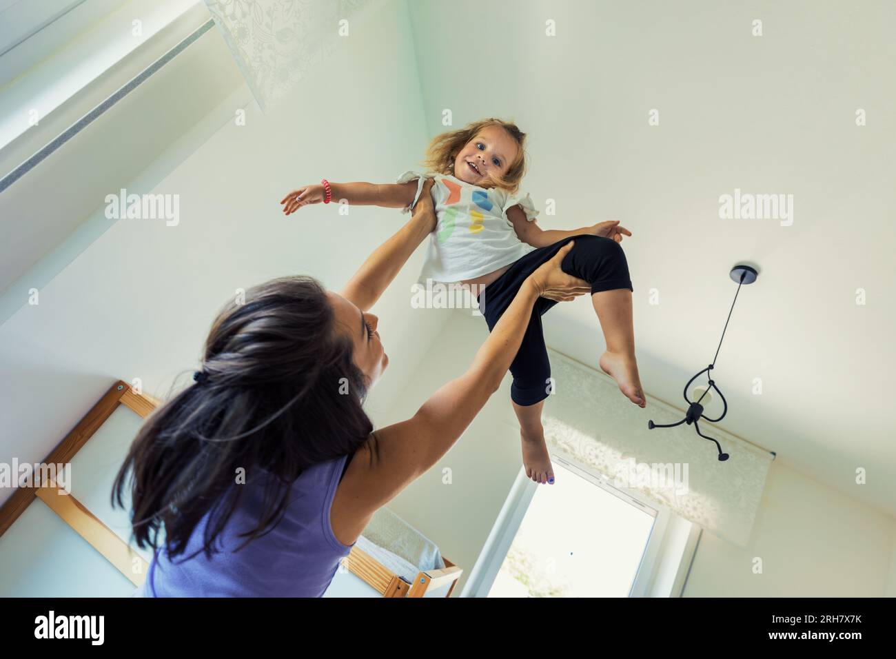 Mom playfully makes daughter fly in room; hands and feet climbing ...