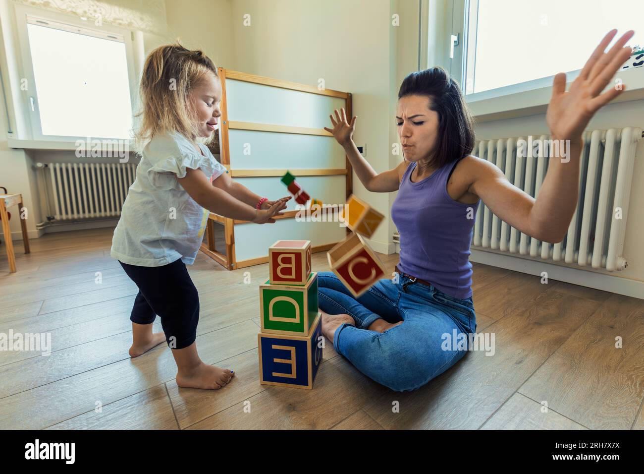 Blonde daughter and mother enjoy playtime with wooden toys in the ...