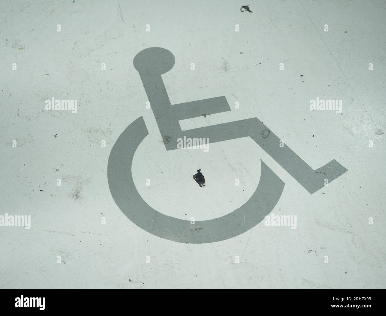 A wheelchair symbol is painted on the street. It marks a parking lot ...