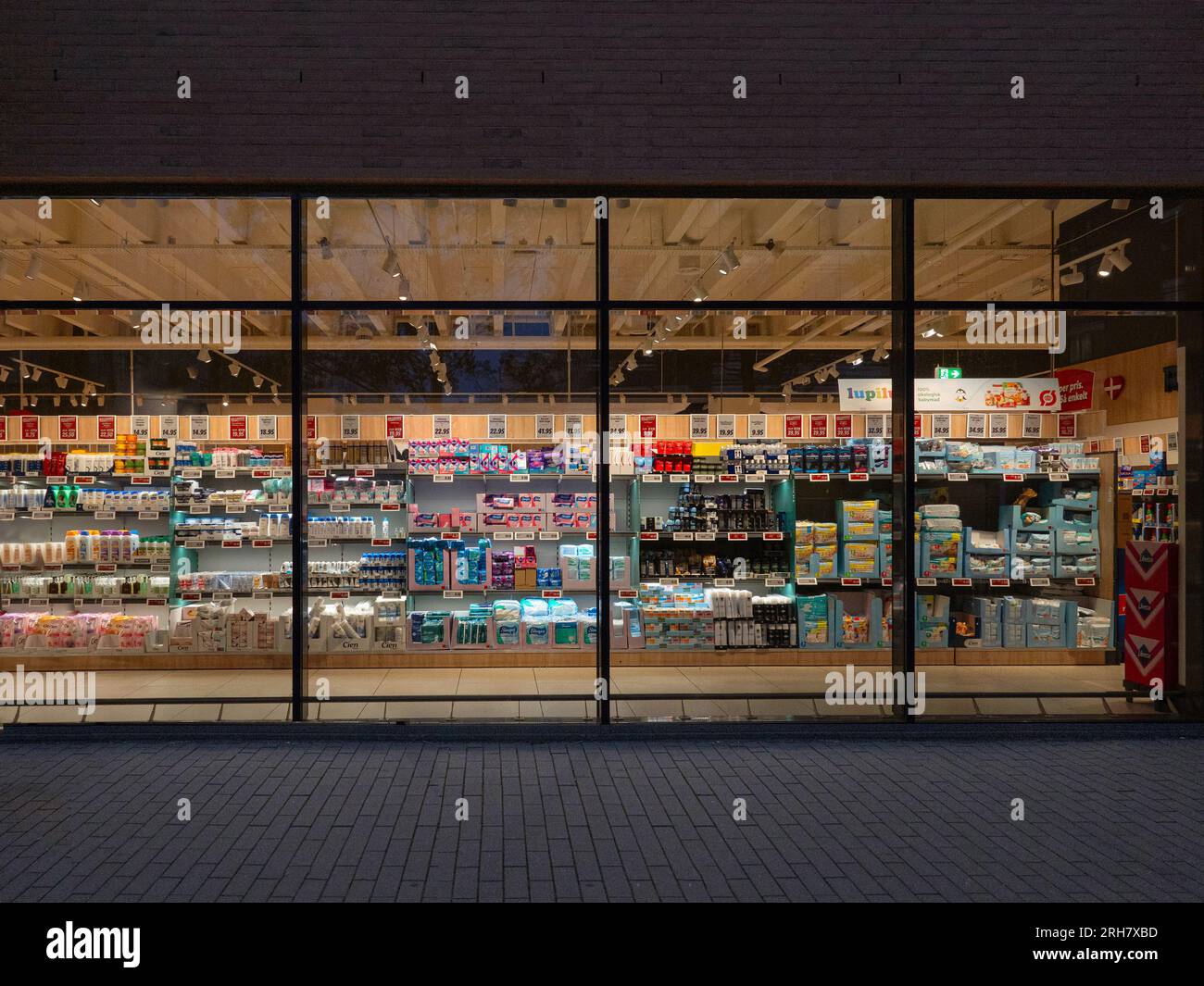 A look through a window in a empty supermarket at night time ...