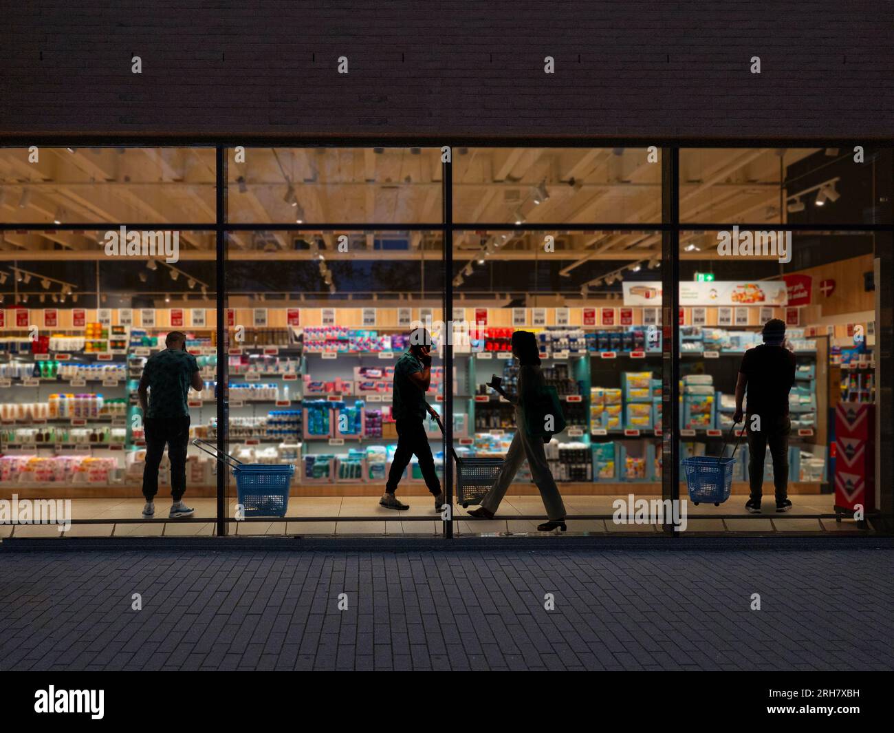 A look through a window in a supermarket at night. People go shopping ...