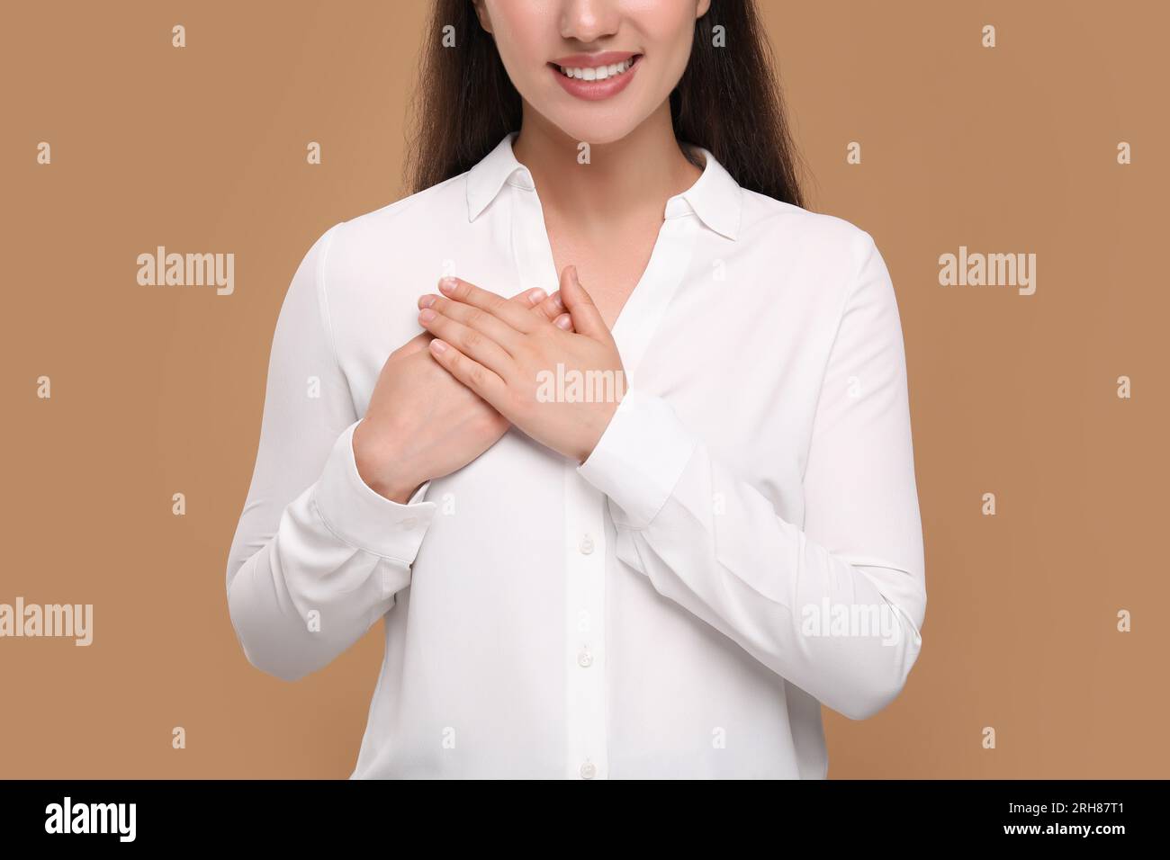 Thank you gesture. Grateful woman with hands on chest against brown ...