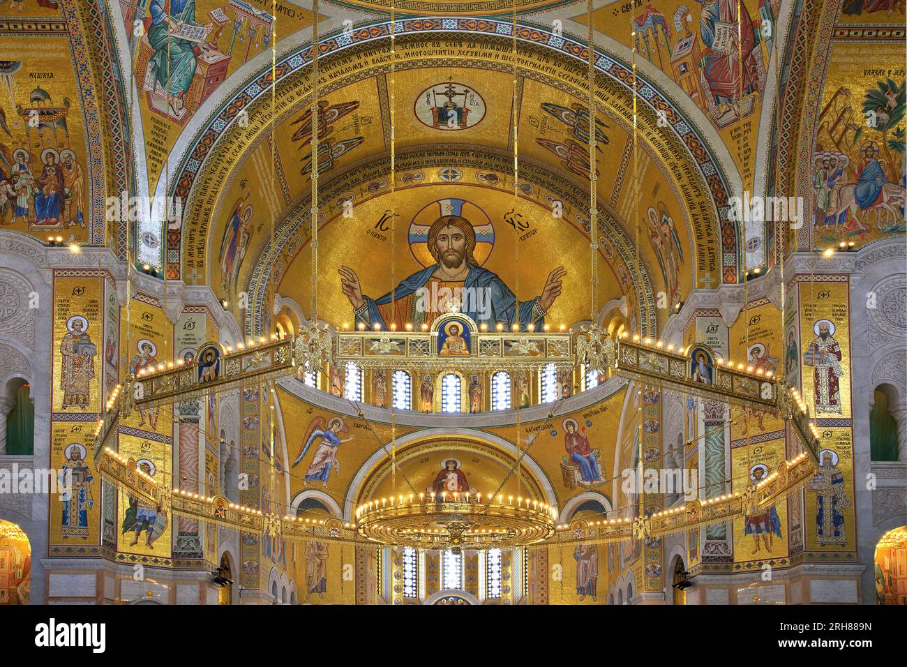 The ornately decorated ceiling with golden frescoes and wheel chandelier at the Church of Saint ...