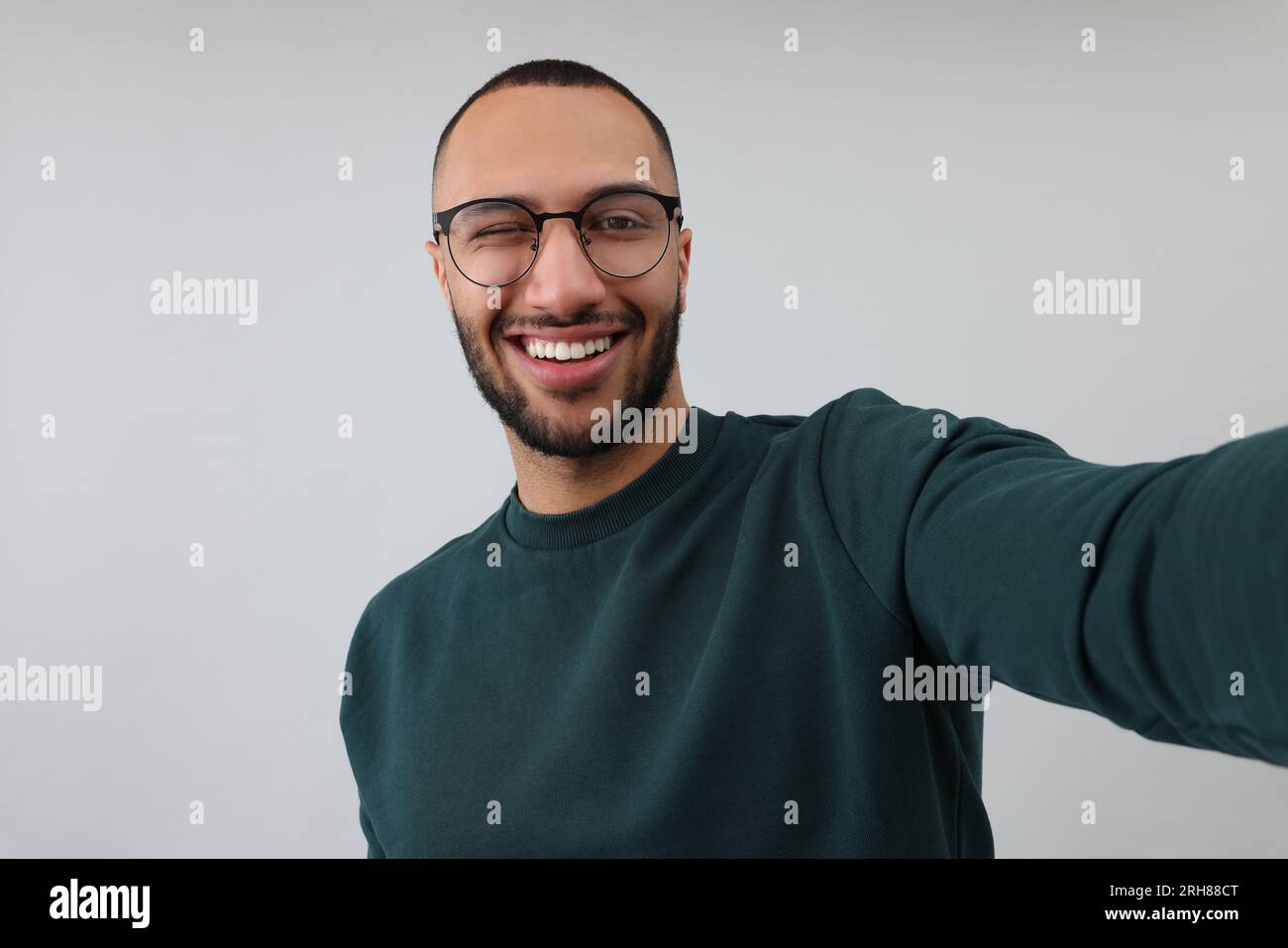 Smiling young man taking selfie on grey background Stock Photo - Alamy