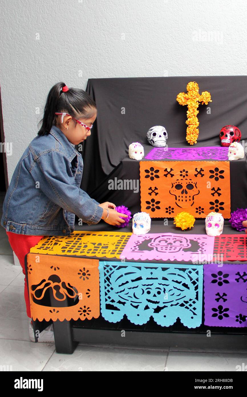 Mexican child girl put the altar and offering of the Day of the Dead in ...
