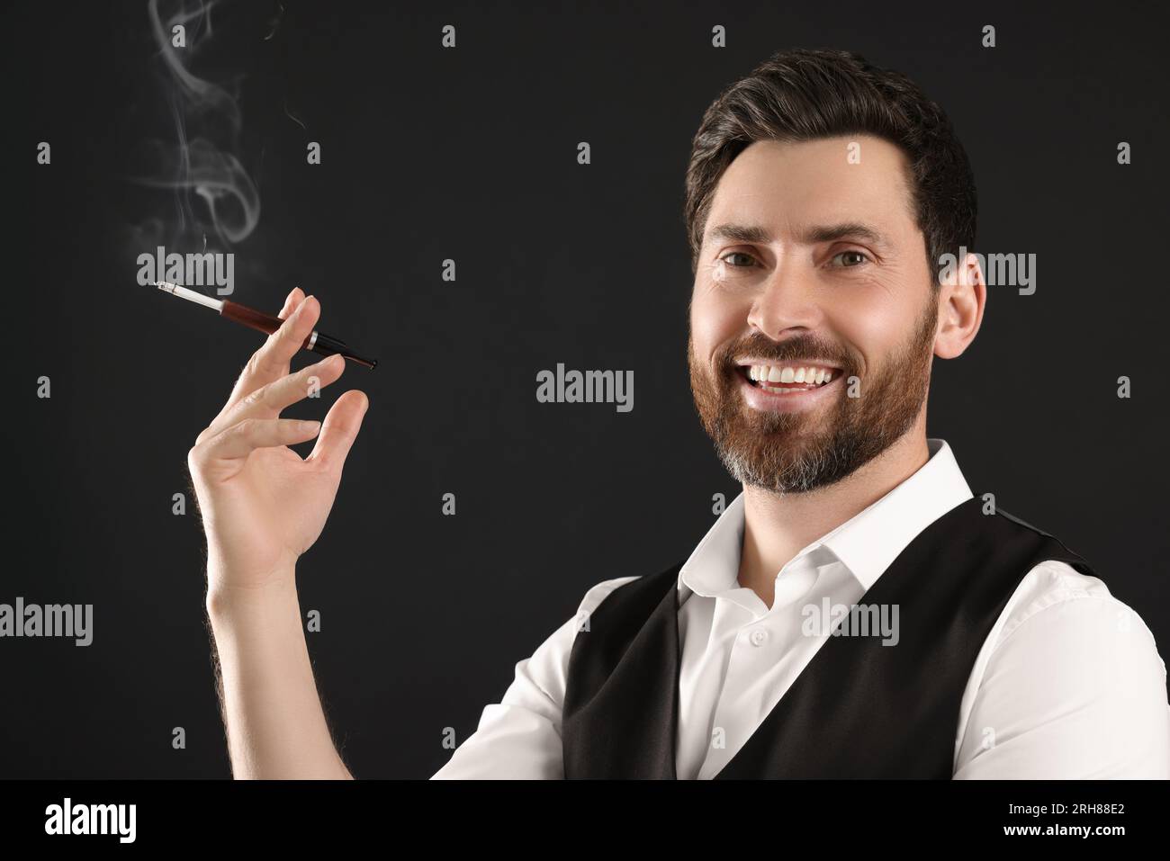 Man using cigarette holder for smoking on black background Stock Photo ...