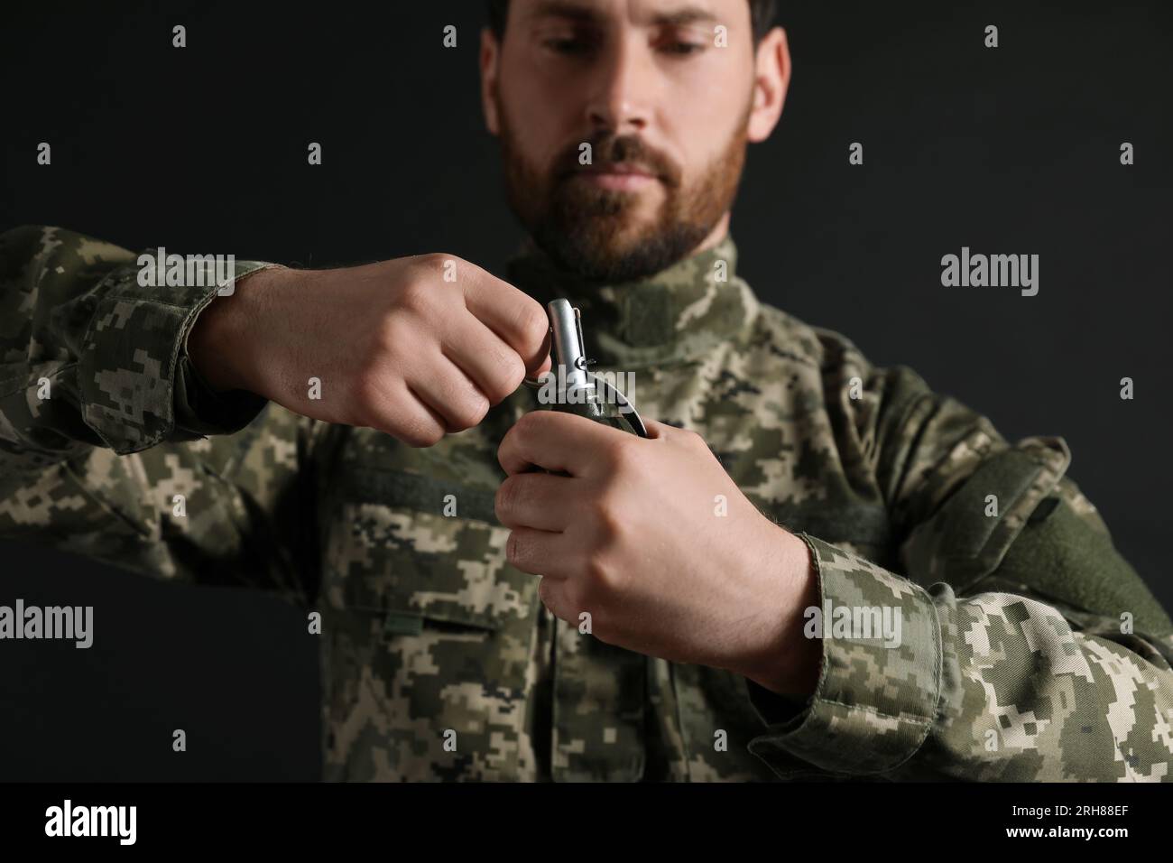 Soldier pulling safety pin out of hand grenade on black background ...