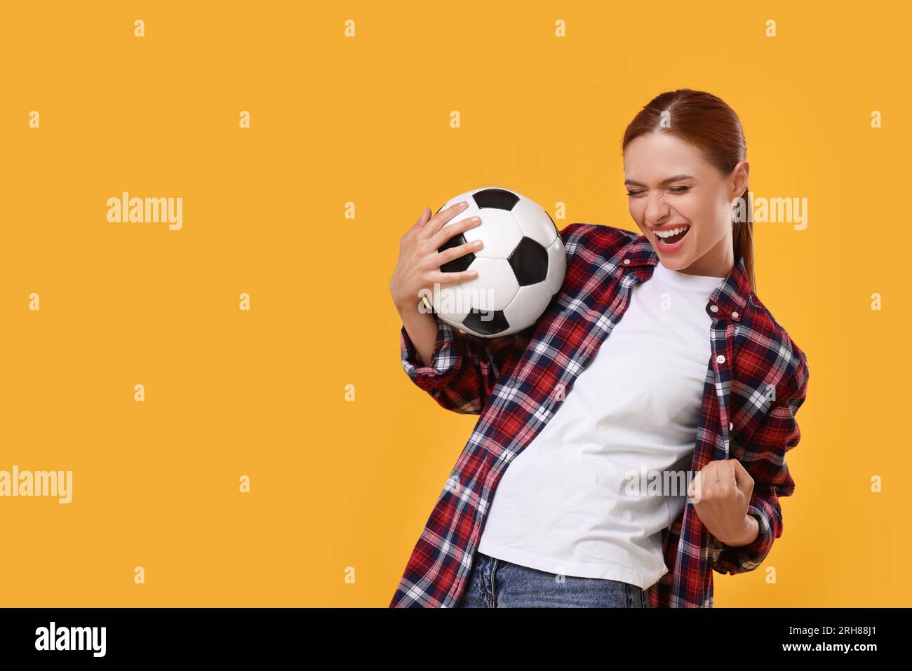 Emotional fan holding football ball and celebrating on yellow ...