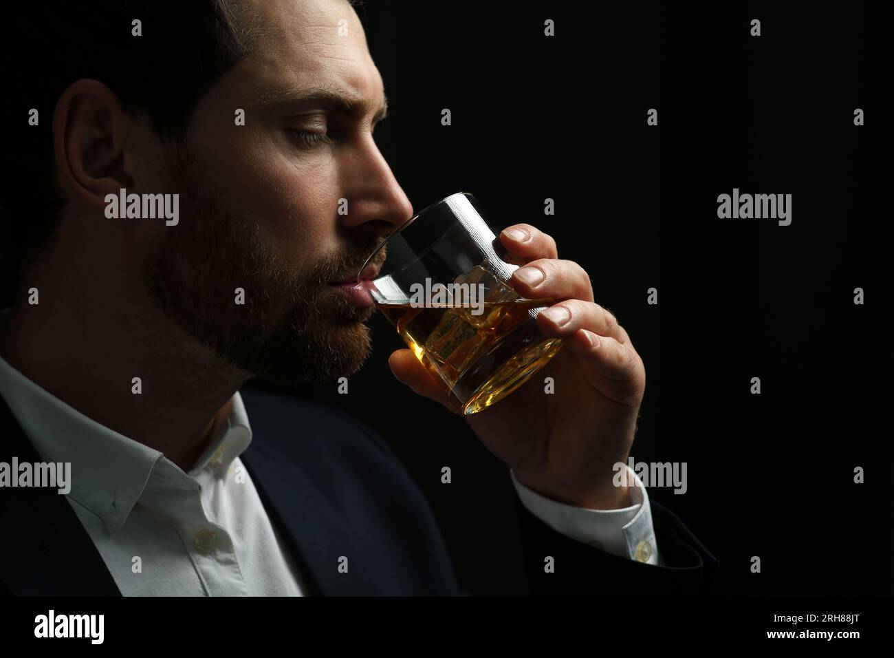 Man in suit drinking whiskey on black background Stock Photo - Alamy