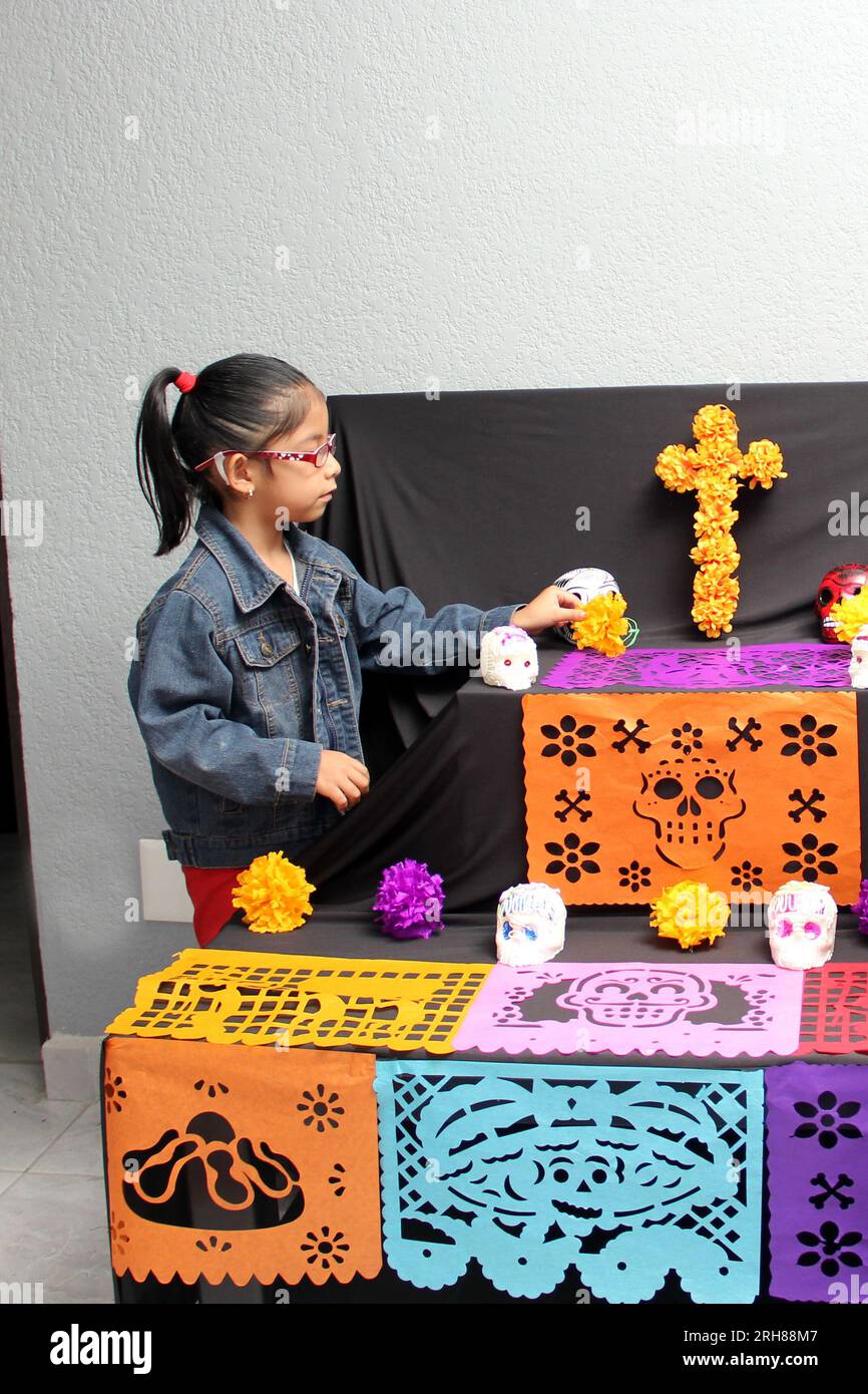 Mexican child girl put the altar and offering of the Day of the Dead in ...