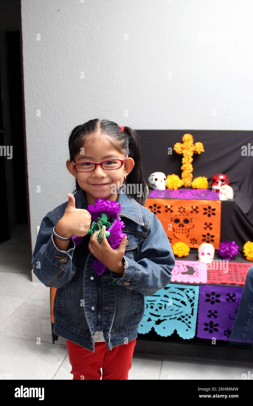 Mexican child girl put the altar and offering of the Day of the Dead in ...