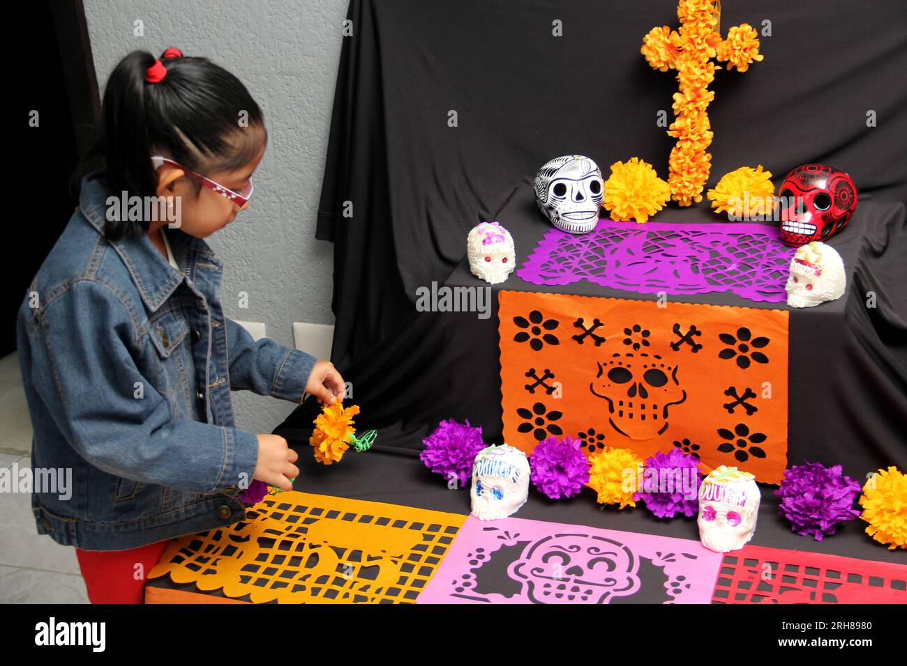 Mexican child girl put the altar and offering of the Day of the Dead in ...